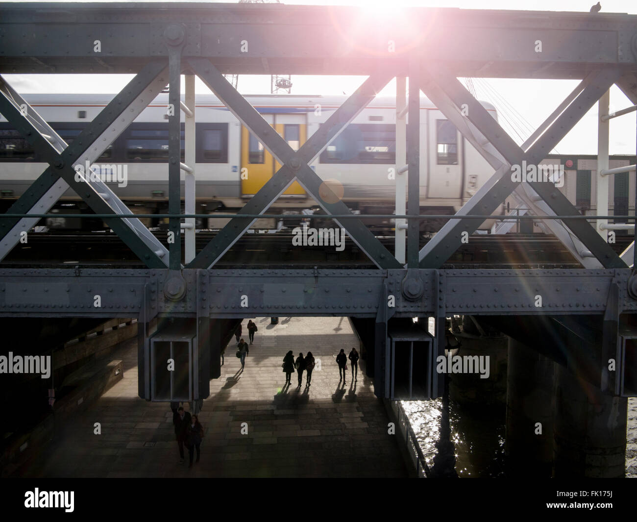 Hungerford railway bridge with a train and commuters below Stock Photo ...