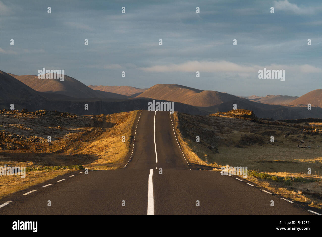 Horizontal photo at sunset of a straight asphalt road going into the ...