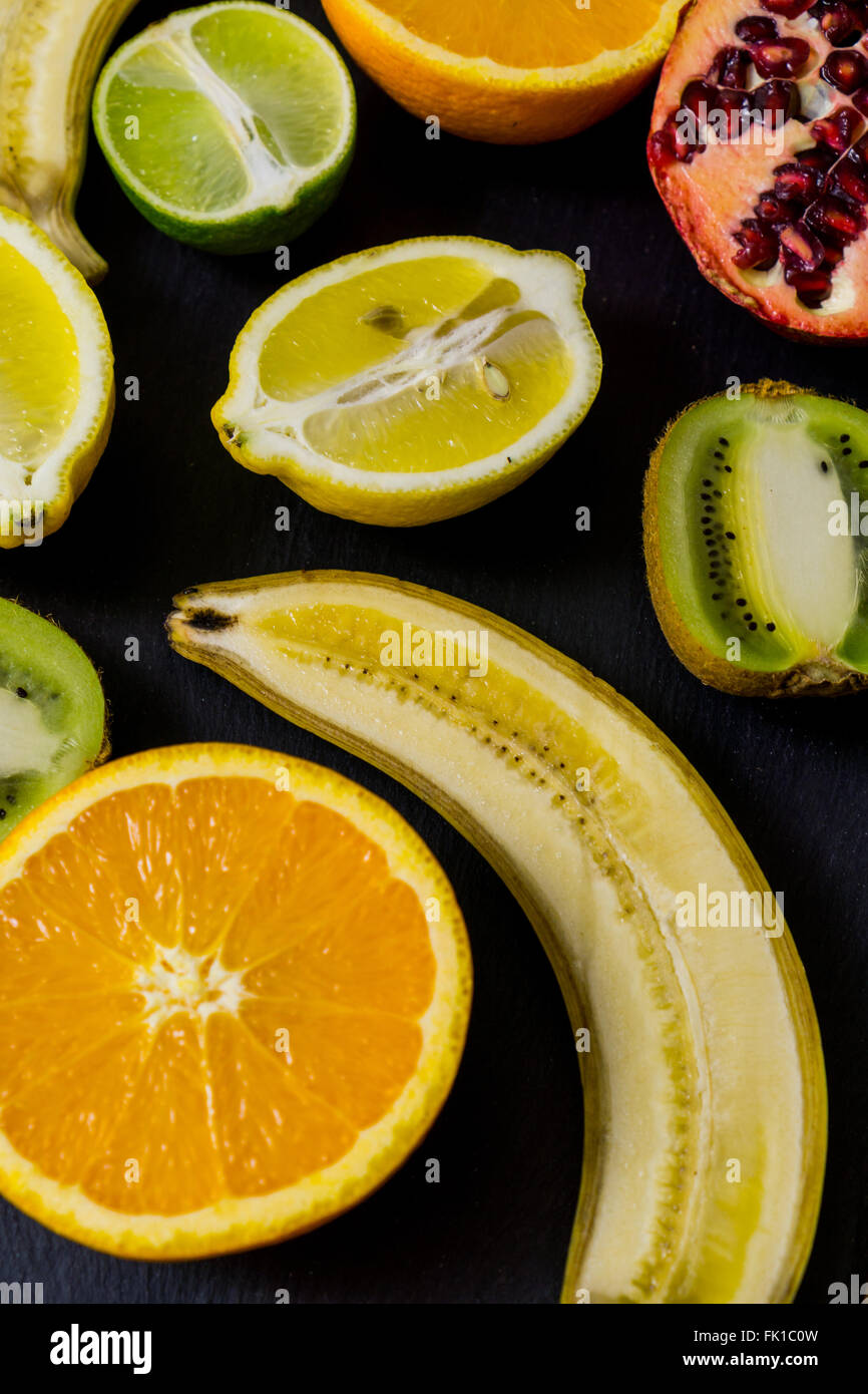 Group of mixed fruits cut in half on a dark board, section Stock Photo ...