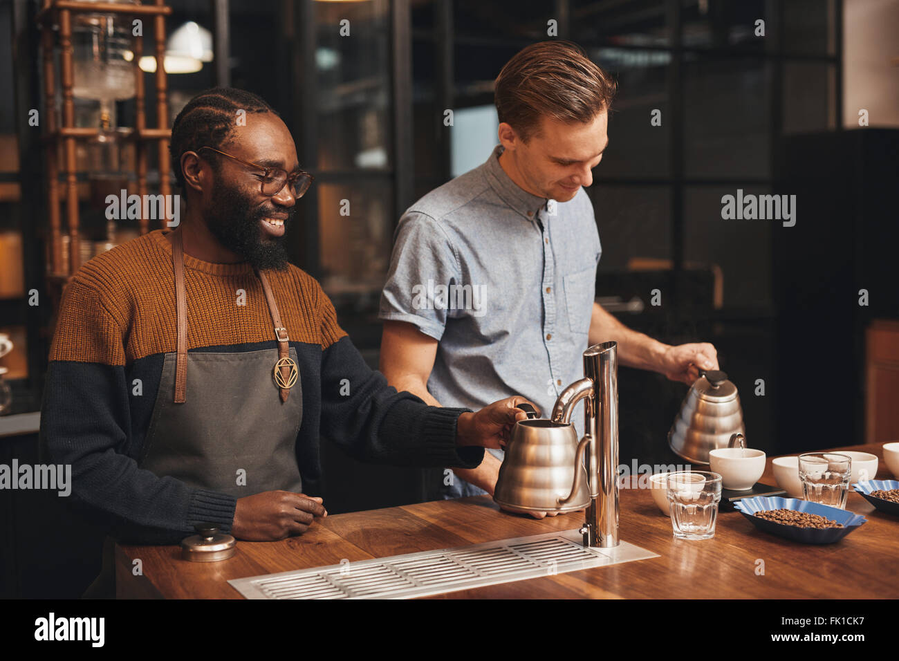 African roastery manager training a barista at wooden counter Stock ...