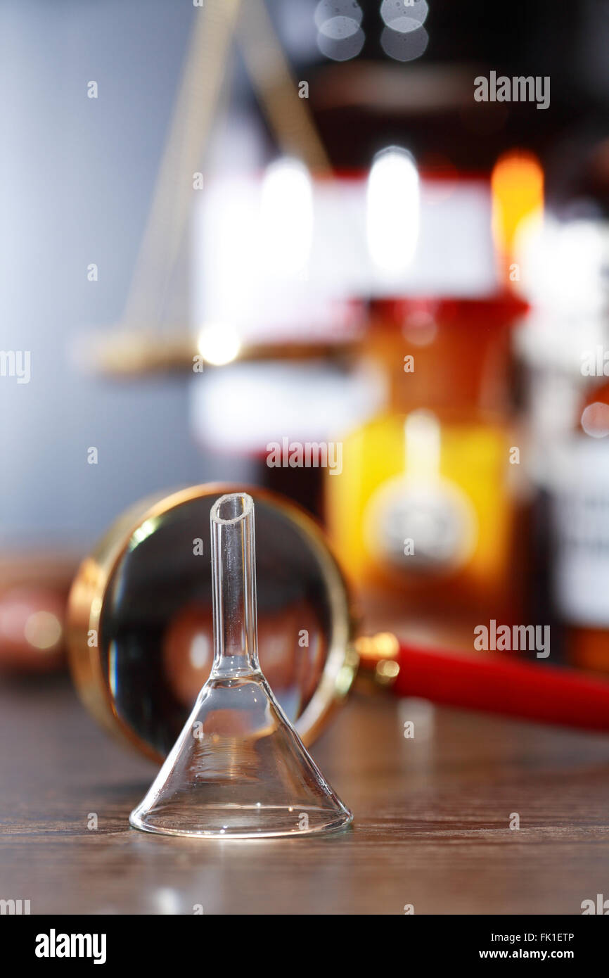 Chemical funnel near magnifying glass against blurred background with ...