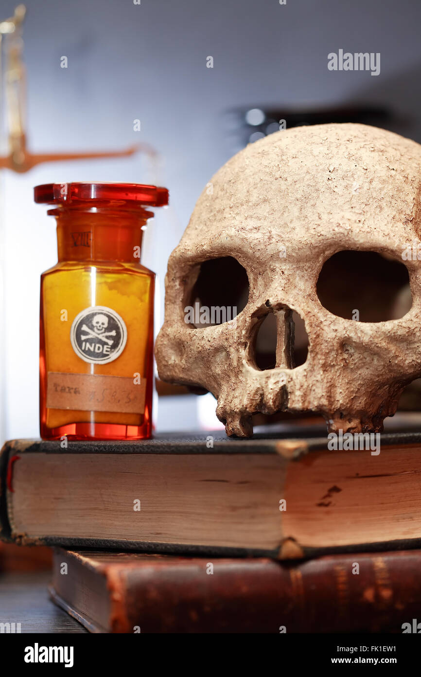 Medical laboratory. Human skull on old book near flask with poison ...