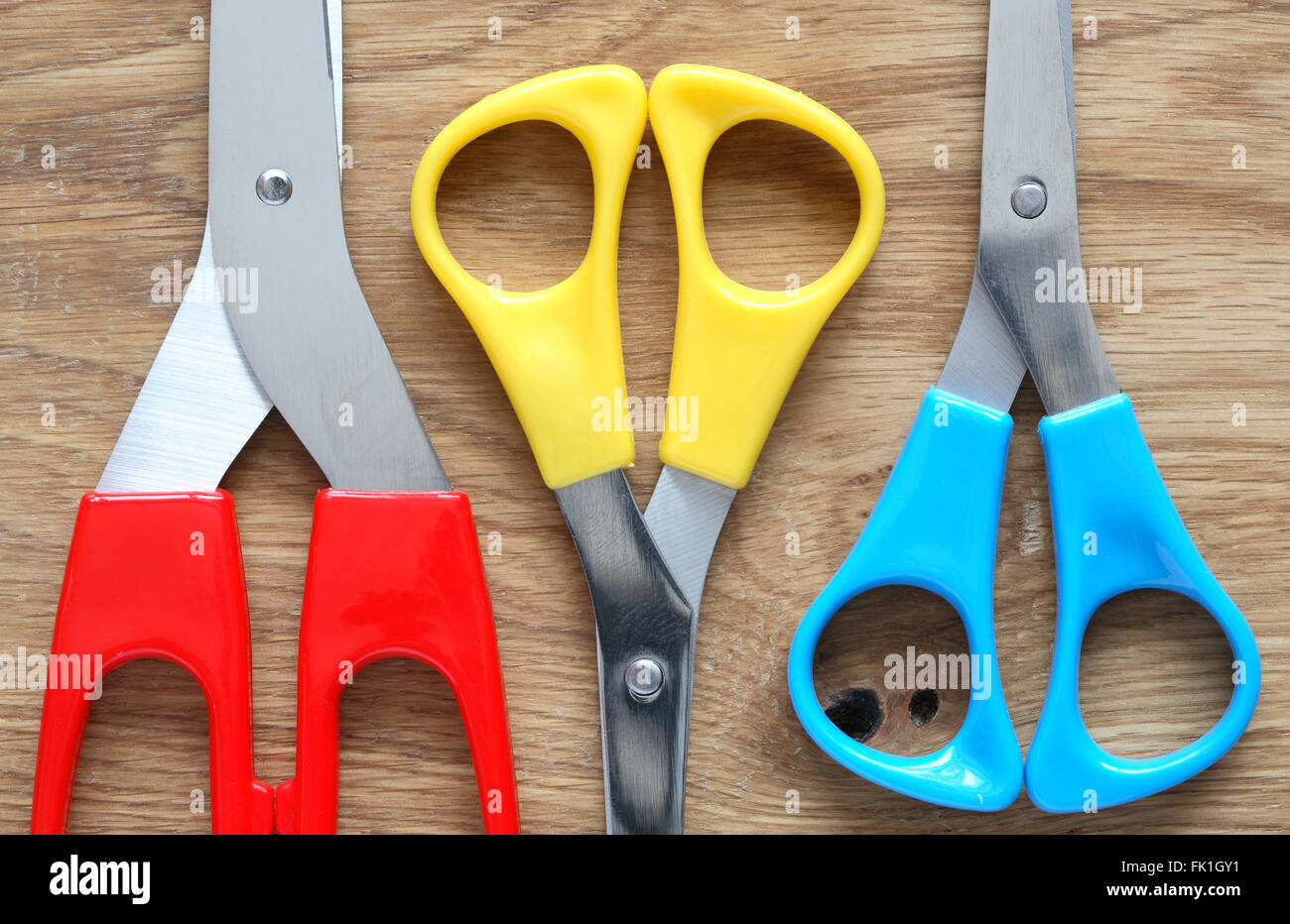 Set of various colored scissors on wooden board Stock Photo - Alamy
