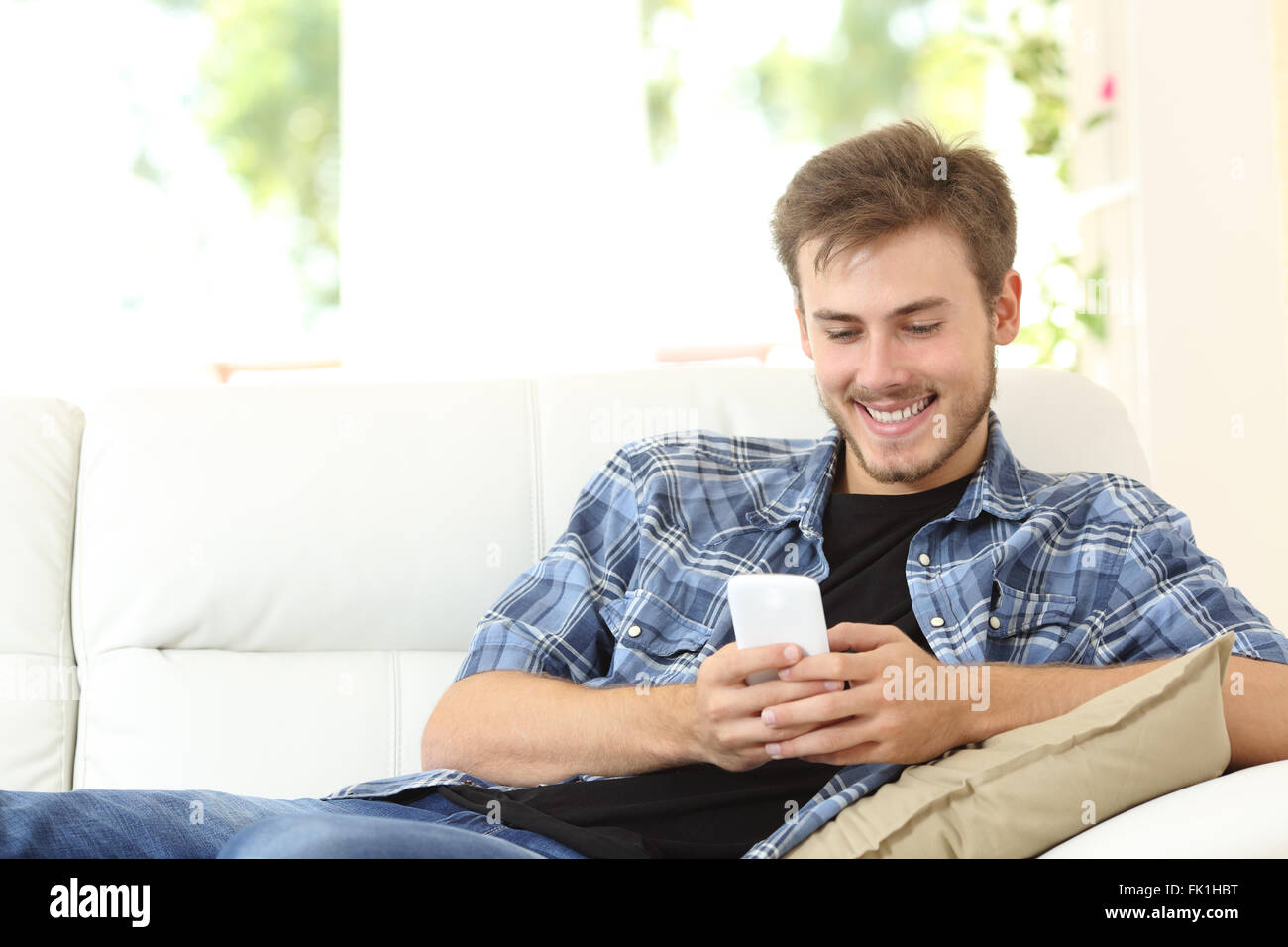 Man using a smart phone at home sitting on a couch at home Stock Photo ...