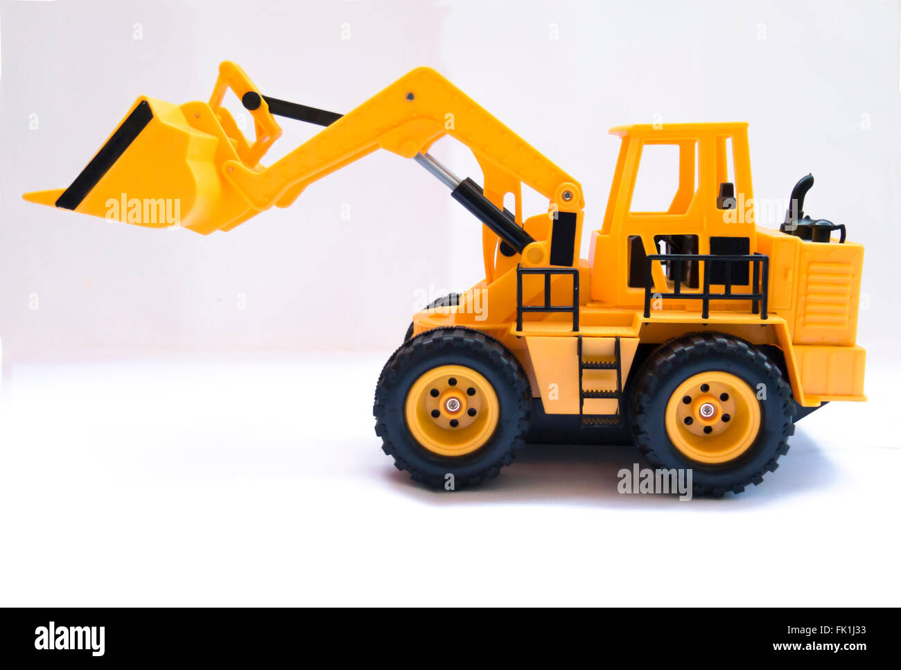 yellow toy excavator, bucket raised, on a white background Stock Photo ...