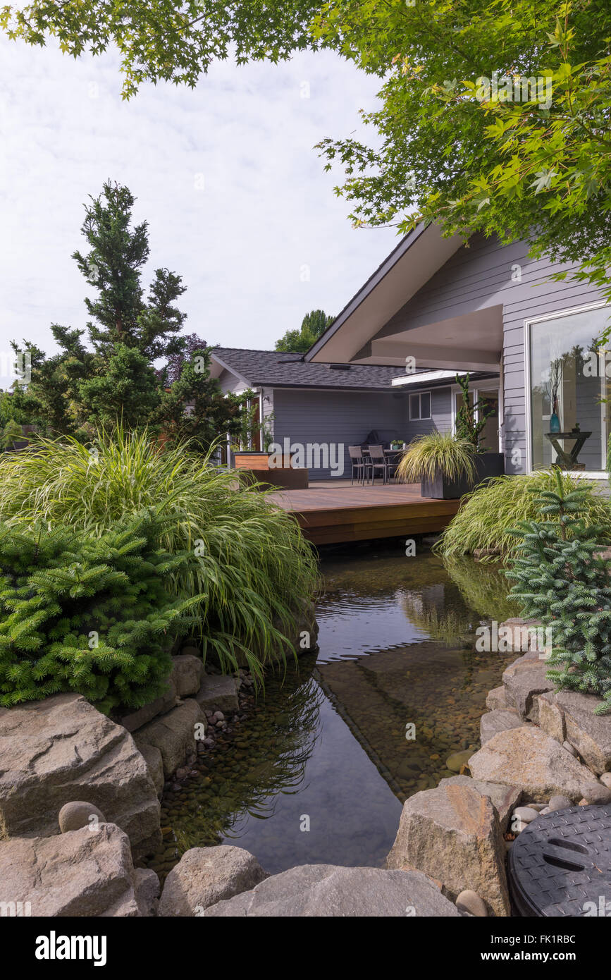 A water feature emulating a creek flows under a deck and between ...