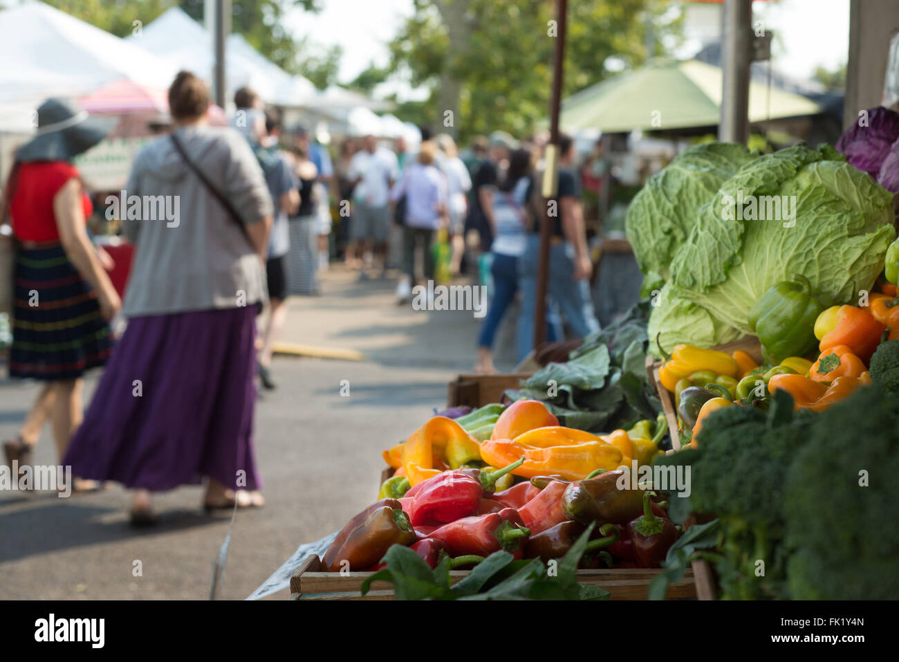 Colorful fresh produce are highlighted in the foreground with a busy ...