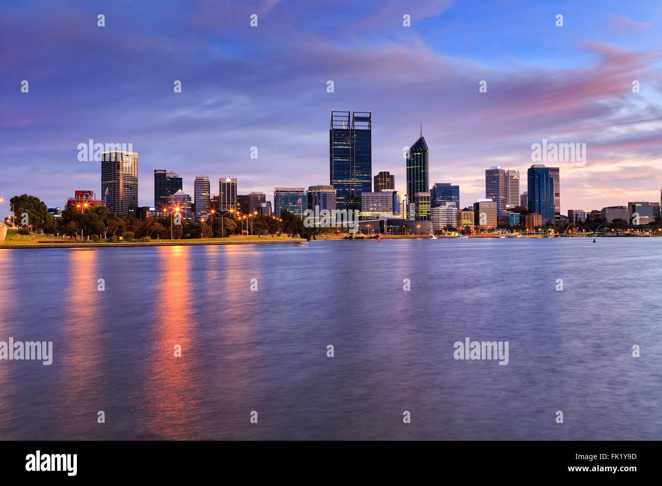 Perth city CBD across wide Swan river at sunrise. Illuminated towers of ...