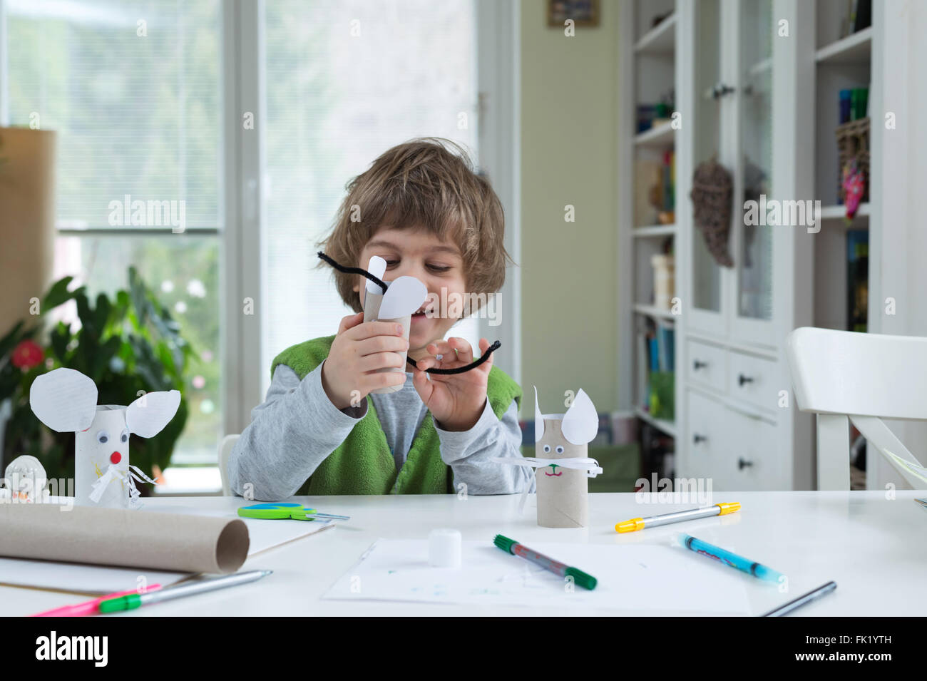 Little boy being creative making homemade paper toys. Supporting ...