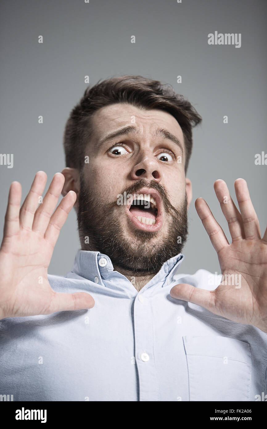 Man wearing a blue shirt is looking scared. Over gray background Stock ...