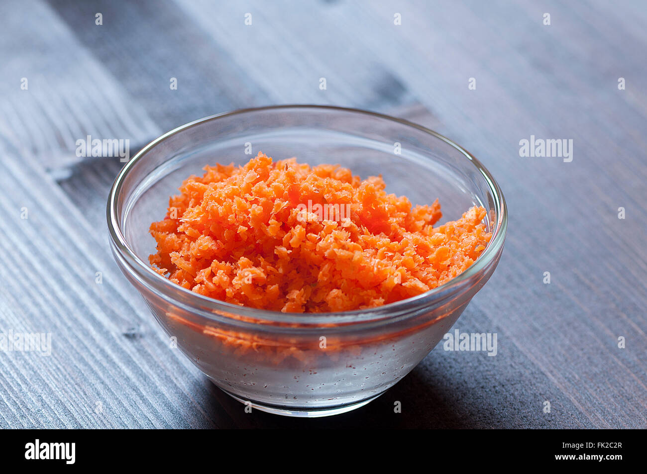 Minced carrots in a glass bowl on a wood background Stock Photo - Alamy