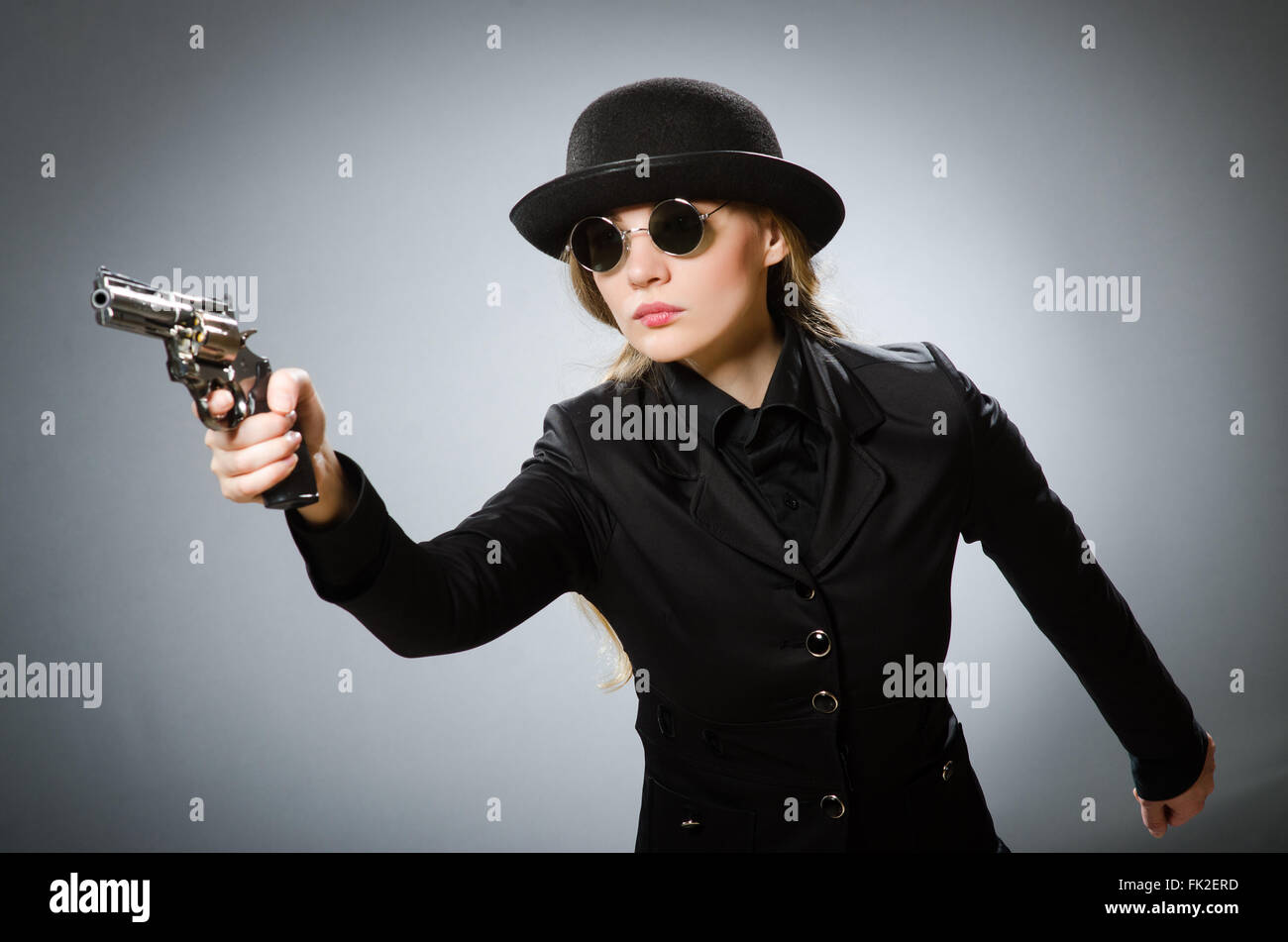 Female spy with weapon against gray Stock Photo - Alamy