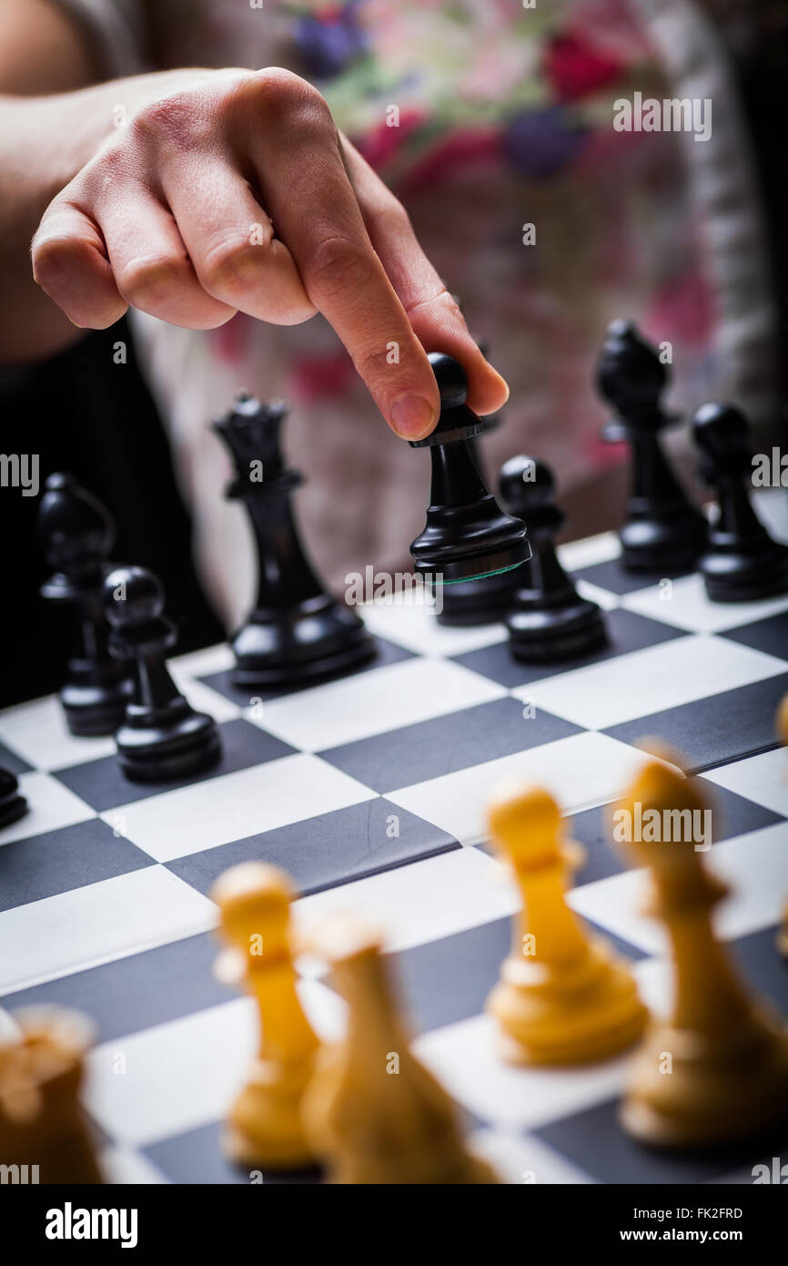 Close-up image of a chess board with chess pieces and a human hand ...
