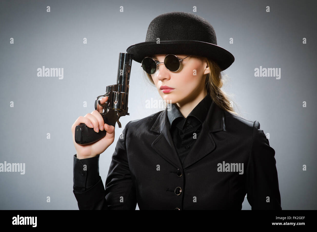Female spy with weapon against gray Stock Photo - Alamy