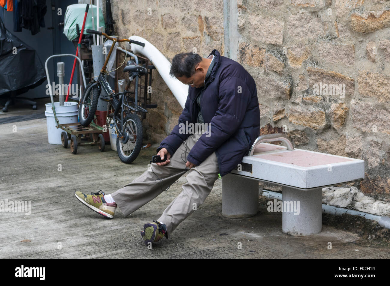 Middle aged Chinese man sleeping while sitting on a bench. Stanley ...