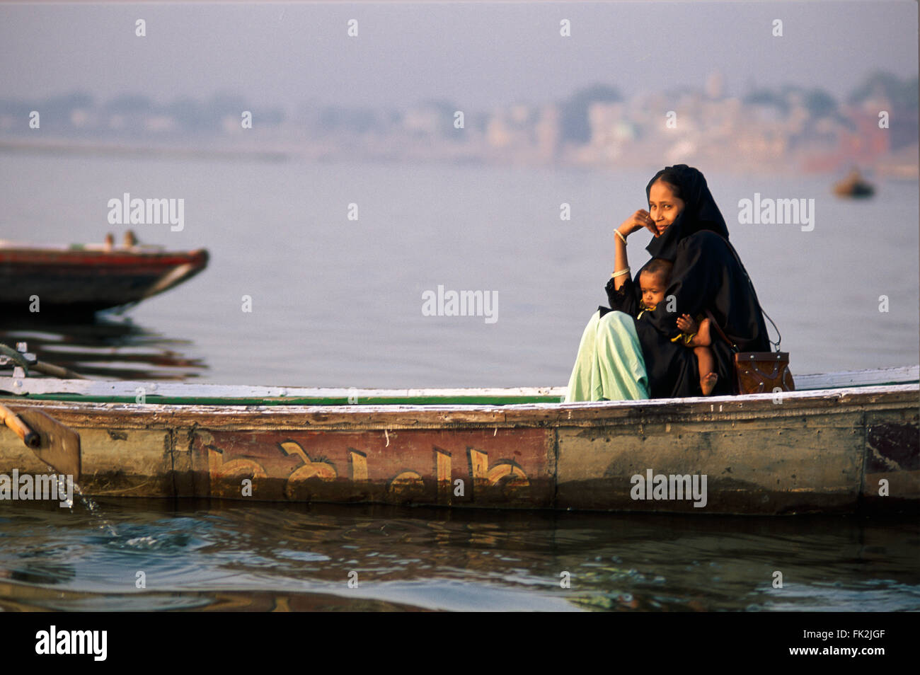 Woman with baby in her arms sailing on a boat by the Ganges river in ...