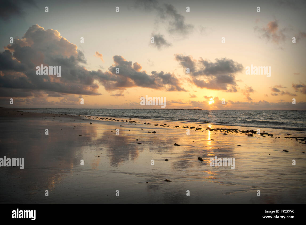 The sun rising over an empty beach and open ocean Stock Photo - Alamy