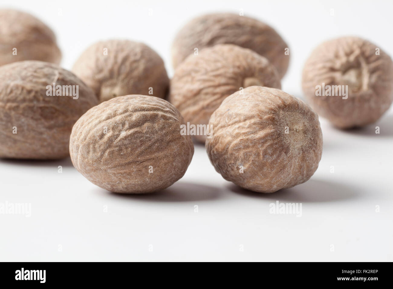 Several whole Nutmeg on a white background Stock Photo - Alamy