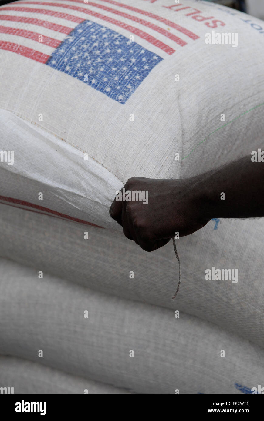 Man pulling sack of maize donated by USAID bearing an American flag ...