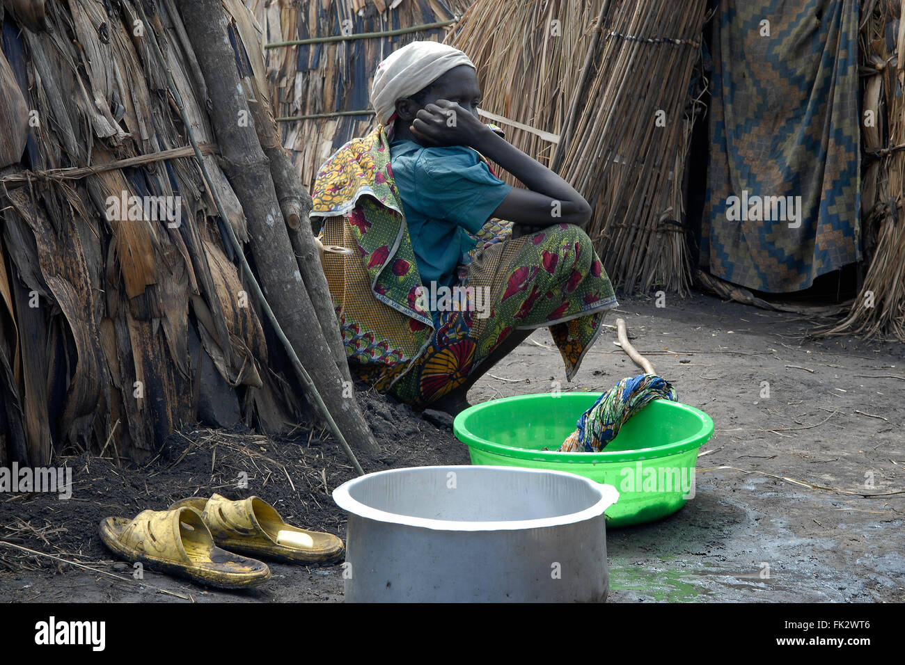 A displaced Congolese woman looks dejected as she sits amid straw huts ...