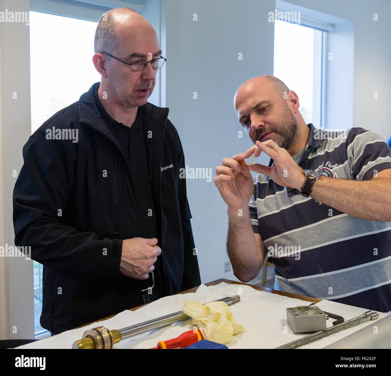 Adult men being taught engineering and pneumatics by qualified engineer ...