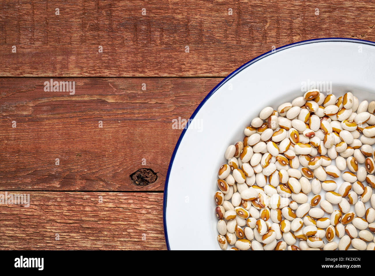 Yellow eye beans on a white metal enamel plate against rustic weathered ...