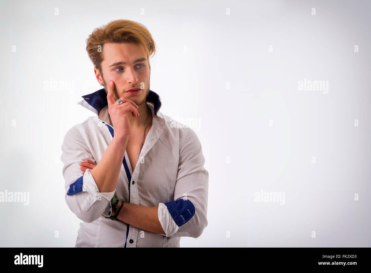 Attractive young man thinking, looking up with hand on his chin, on ...