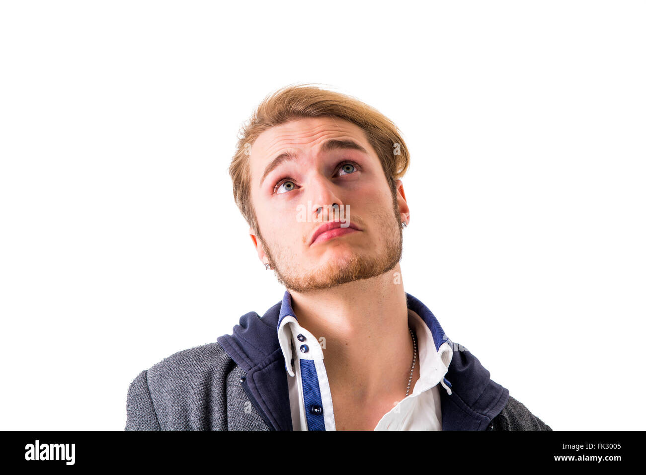 Attractive young man thinking, looking up with hand on his chin ...