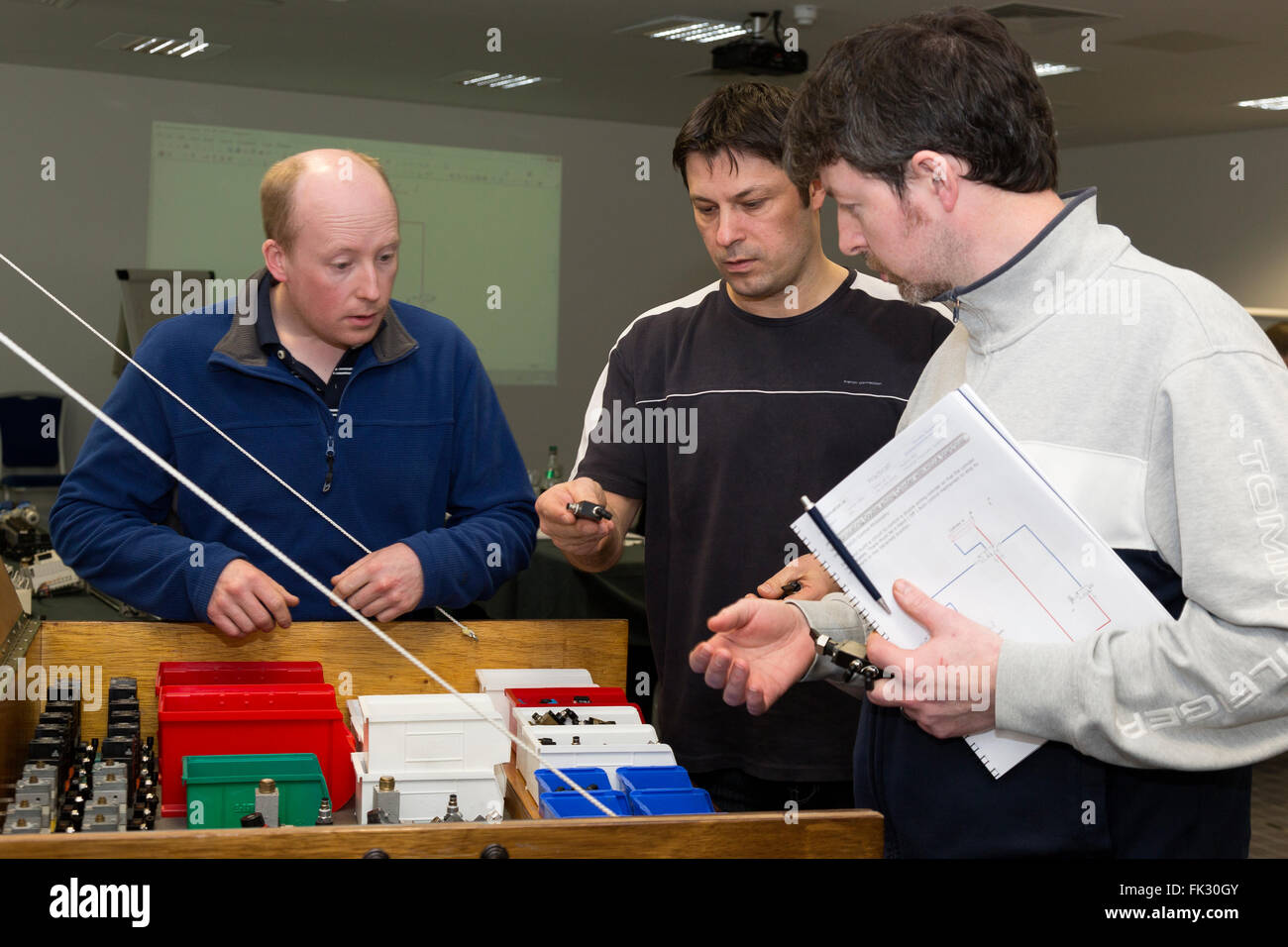 Adult men being taught engineering and pneumatics by qualified engineer ...