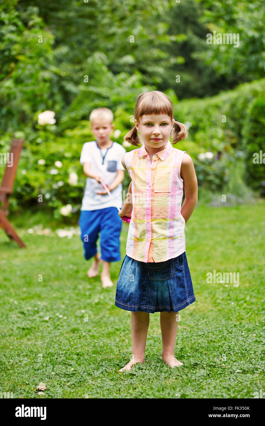 Two children playing together in a garden and pulling a string Stock ...