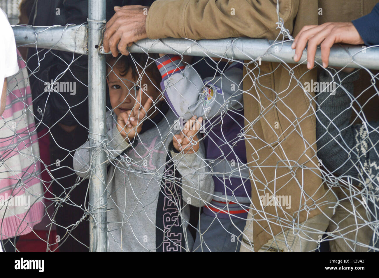 A small child waiting for some food and make the hand symbol of peace ...