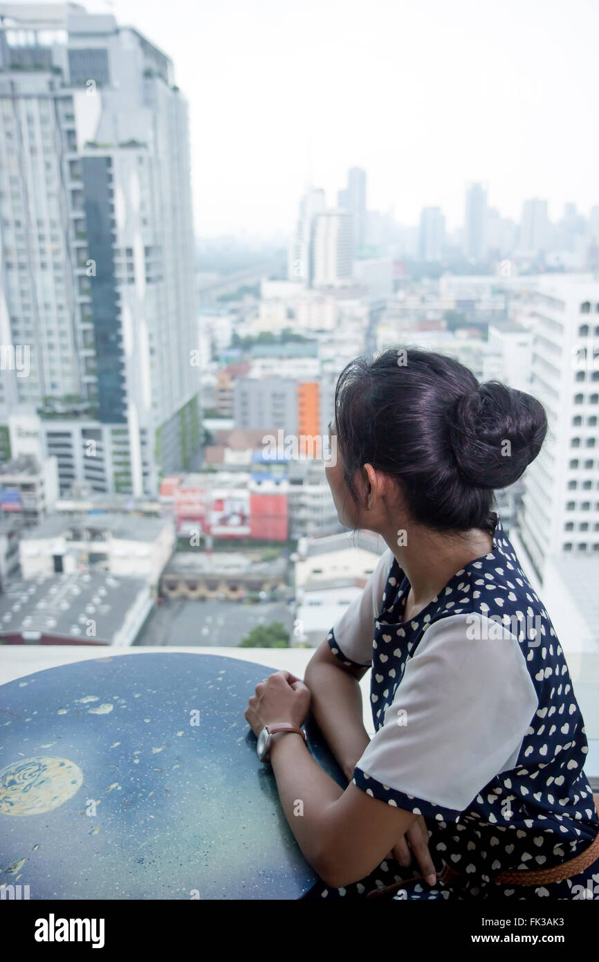 Young woman sitting at a table next to the window in a skyscraper Stock ...