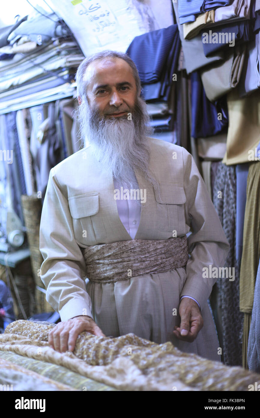 A shopkeeper dressed in traditional clothes selling fabric at Qaysari ...