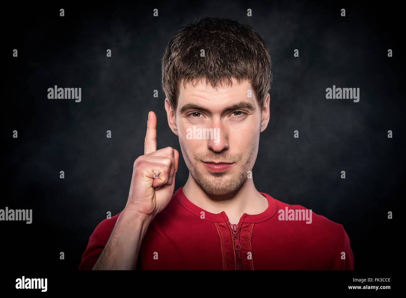 Young man shows finger up Stock Photo - Alamy