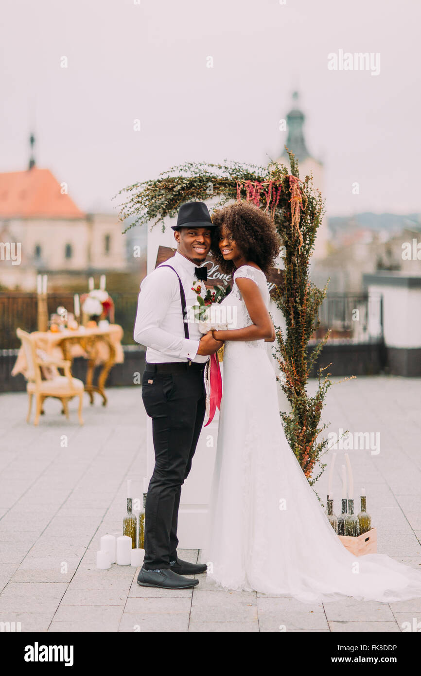 Cheerful black bride and groom holding hands on the wedding ceremony on ...