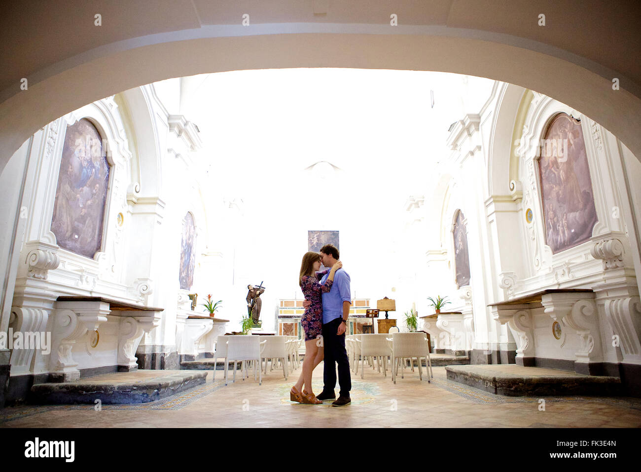 A young and in love couple in an old intimate Italian chapel, they ...