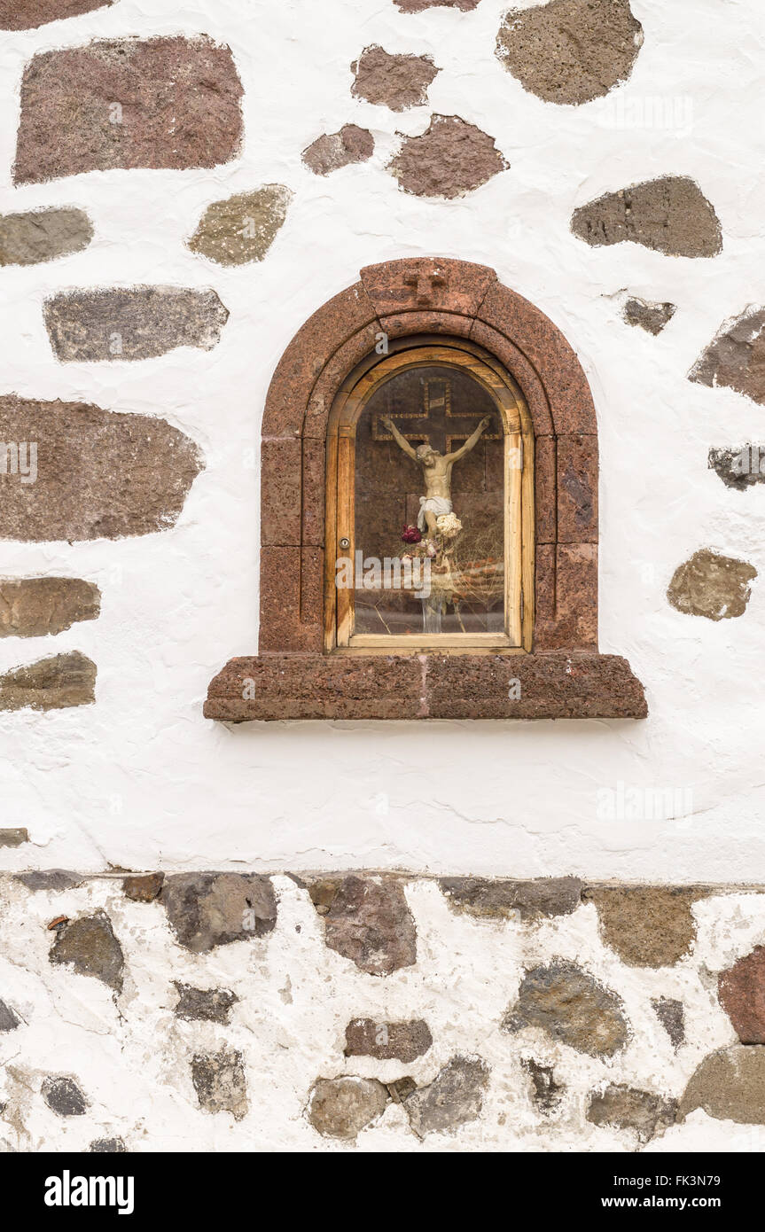 Sculpture of Jesus Christ crucifixion in a niche of the wall, vertical ...