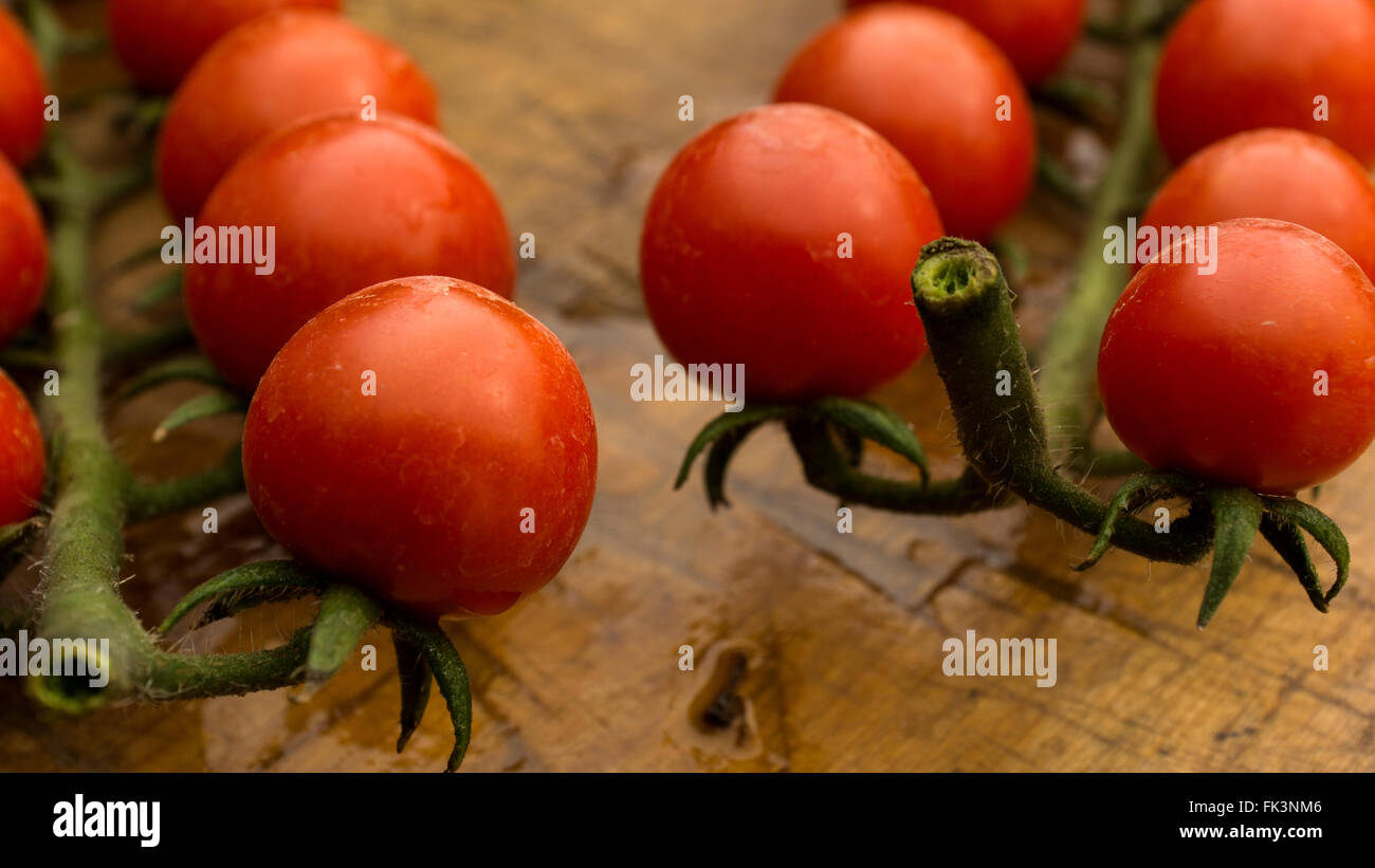 Cherry tomatoes on display on wooden chopping board and wooden table ...
