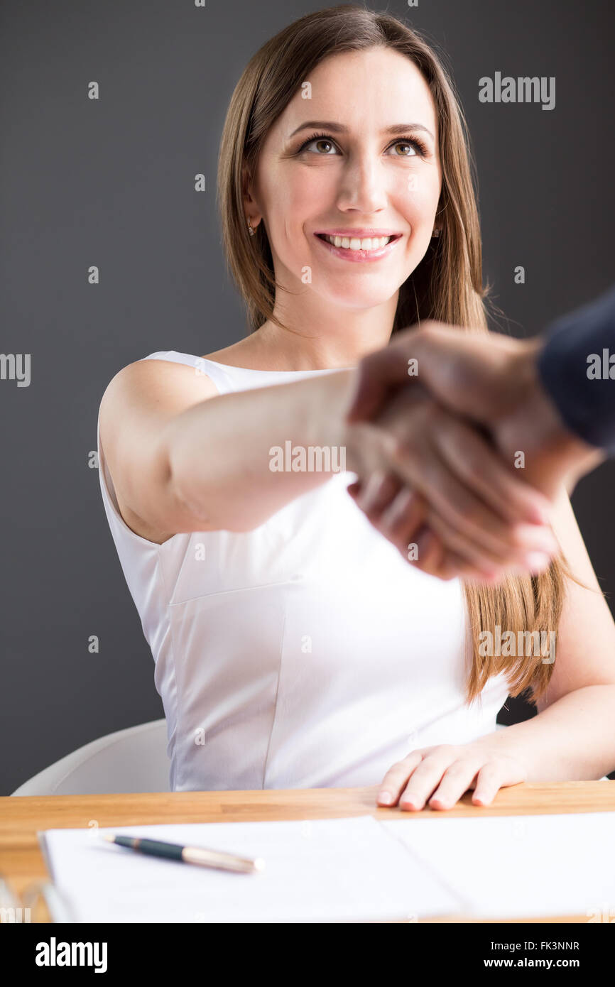 Young smiling business woman in white smart dress shaking hands with ...