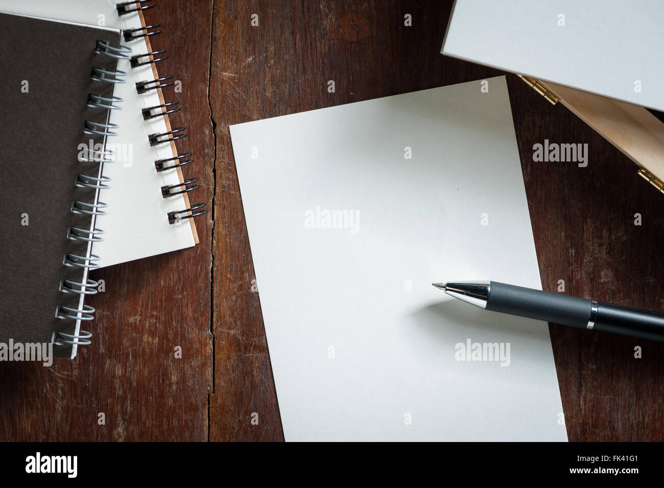 Blank paper on wood table with notebooks on wood table with low key ...