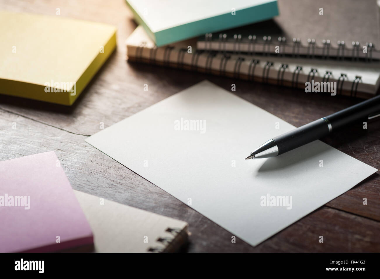 Blank paper on wood table with notebooks on wood table with low key ...