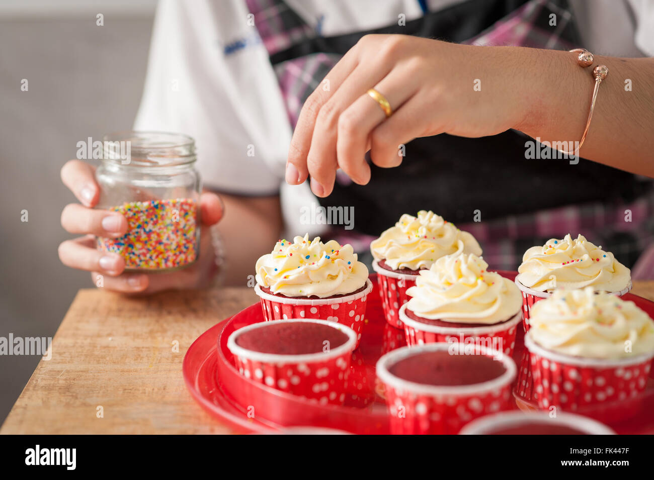 The action of making red velvet cupcakes. Woman hand adding sugar ...