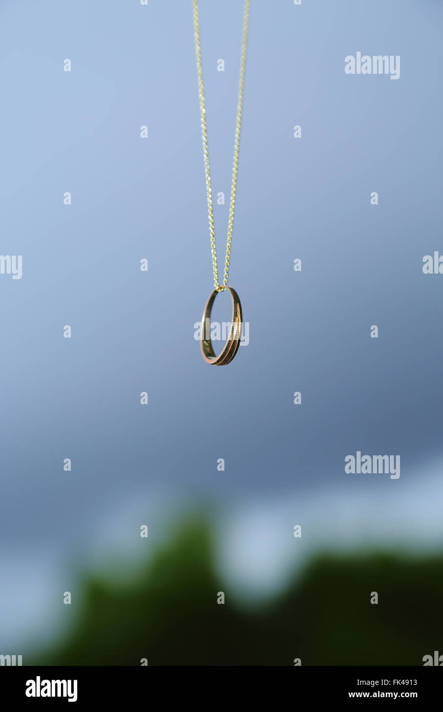 A wedding ring dangling on a chain Stock Photo - Alamy