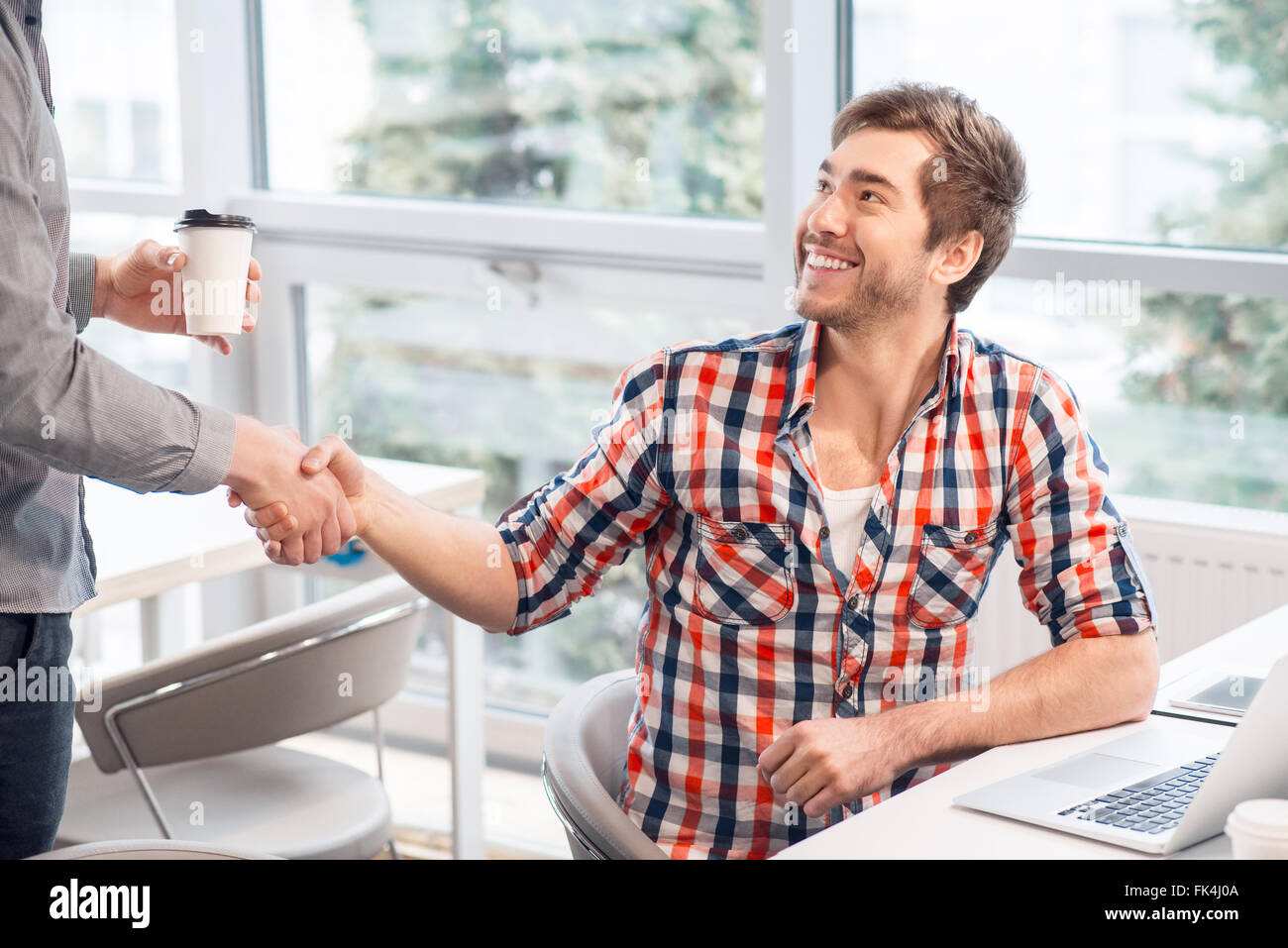 Pleasant man welcoming his colleague Stock Photo - Alamy