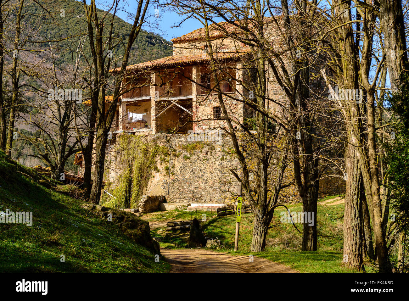 A huge old Spanish farm house is seen through the trees at the end of a ...