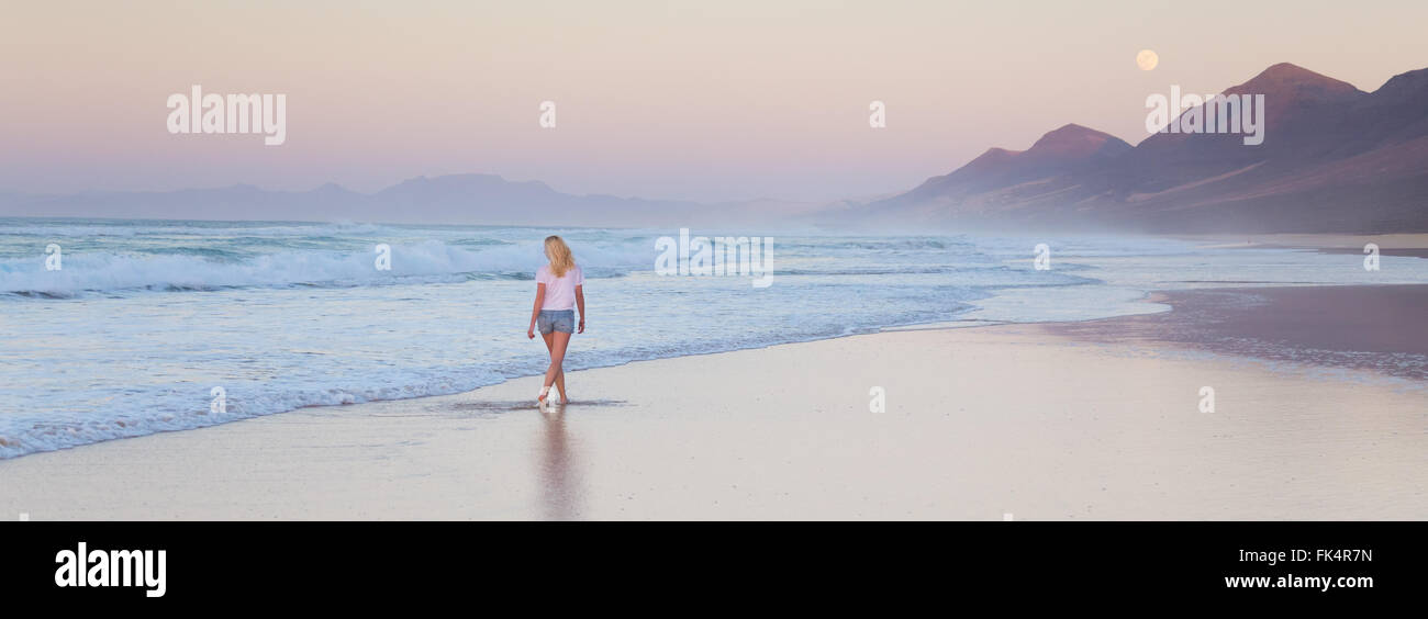 Lady walking on sandy beach in sunset Stock Photo - Alamy