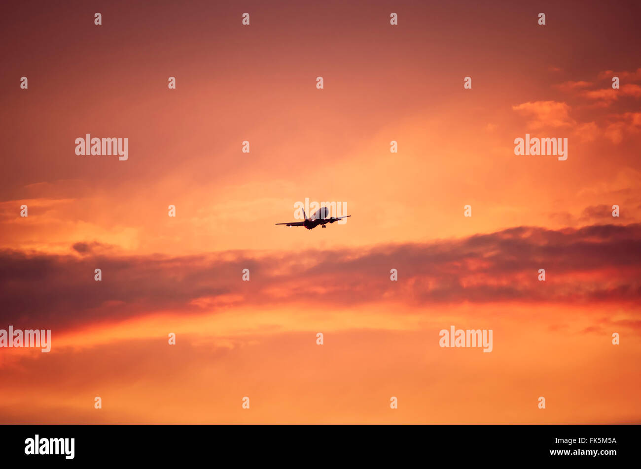 Plane flying upon red and pink sky in the evening Stock Photo - Alamy