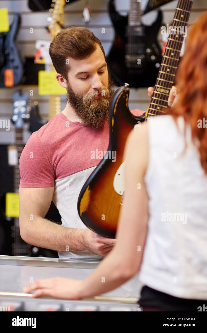 assistant showing customer guitar at music store Stock Photo - Alamy