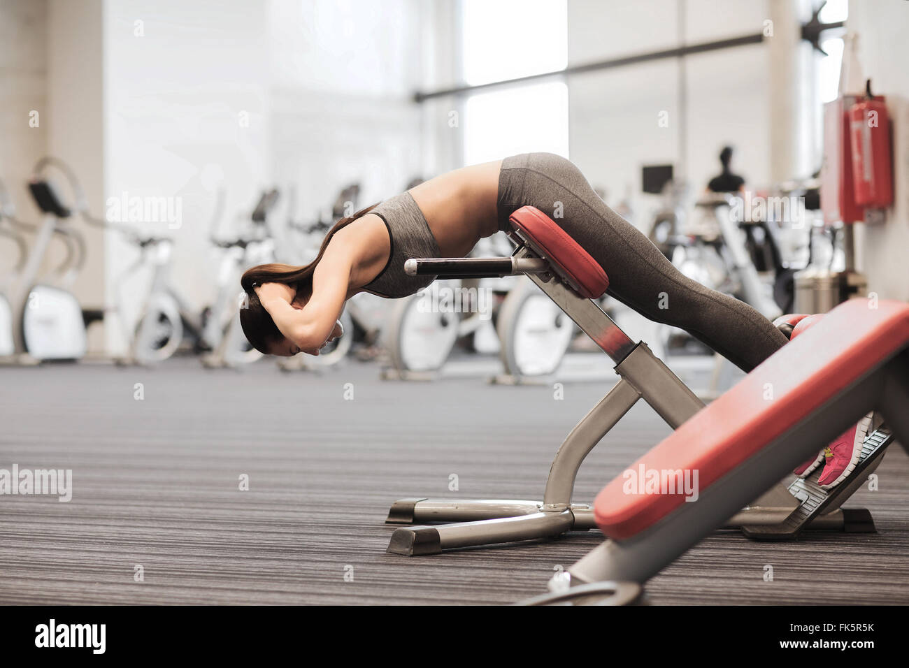 young woman flexing back muscles on bench in gym Stock Photo - Alamy
