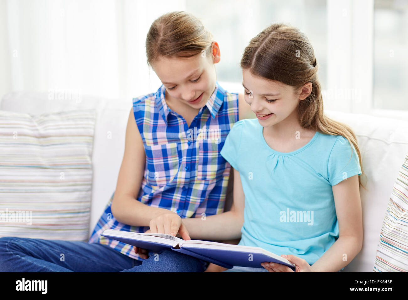 two happy girls reading book at home Stock Photo - Alamy